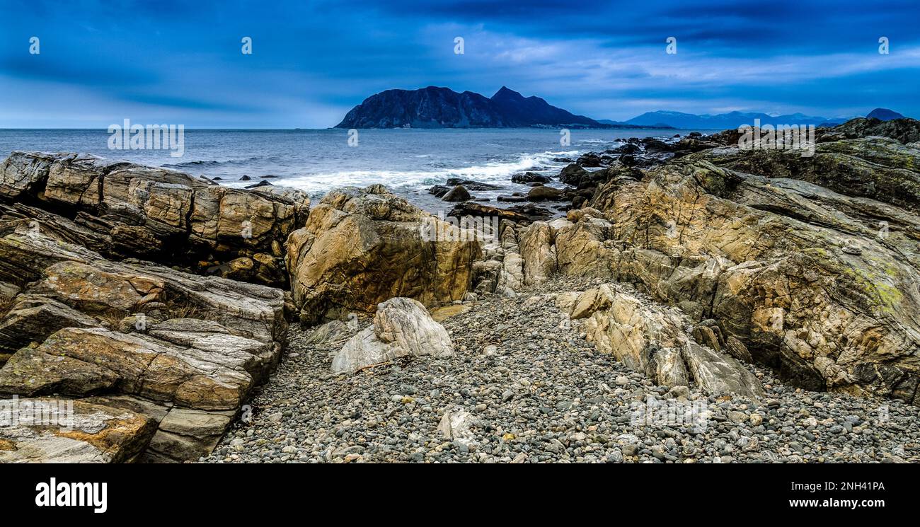 The rugged shoreline features large rocks and pebbles leading to a ...