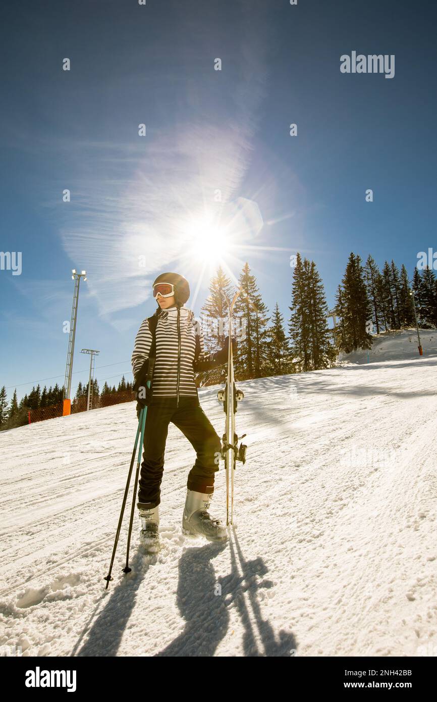 A single young female enjoys a sunny winter day of skiing, dressed in ...
