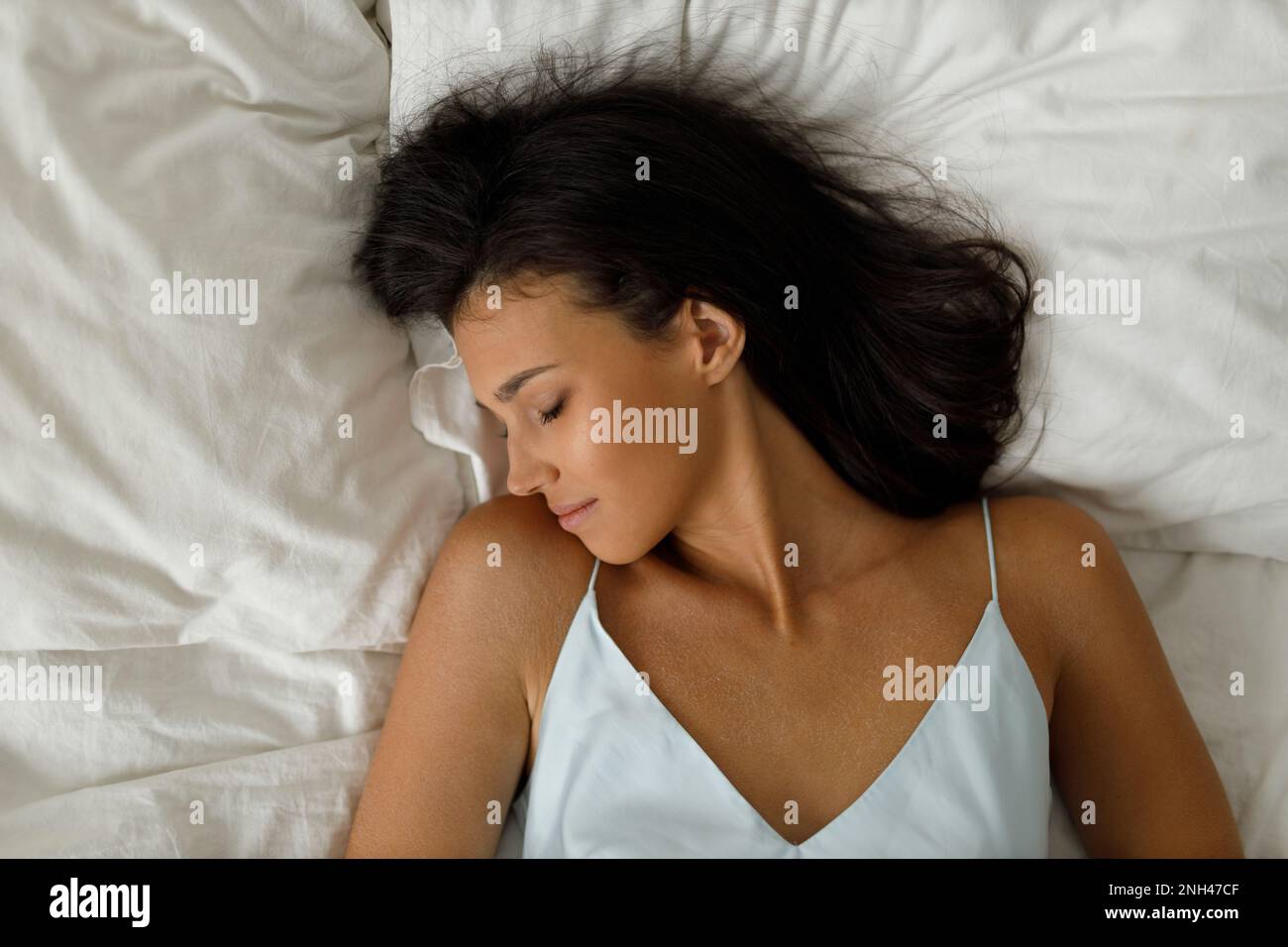 Healthy young woman dressing nightie lying on bed in bedroom. Overhead ...