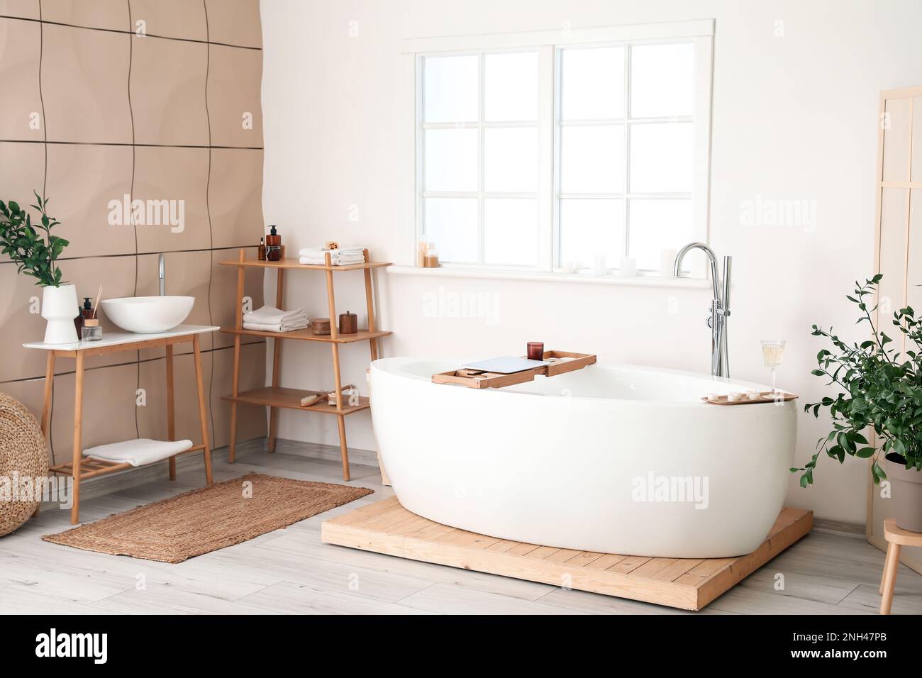 Interior of bathroom with modern bathtub, laptop, champagne and burning ...