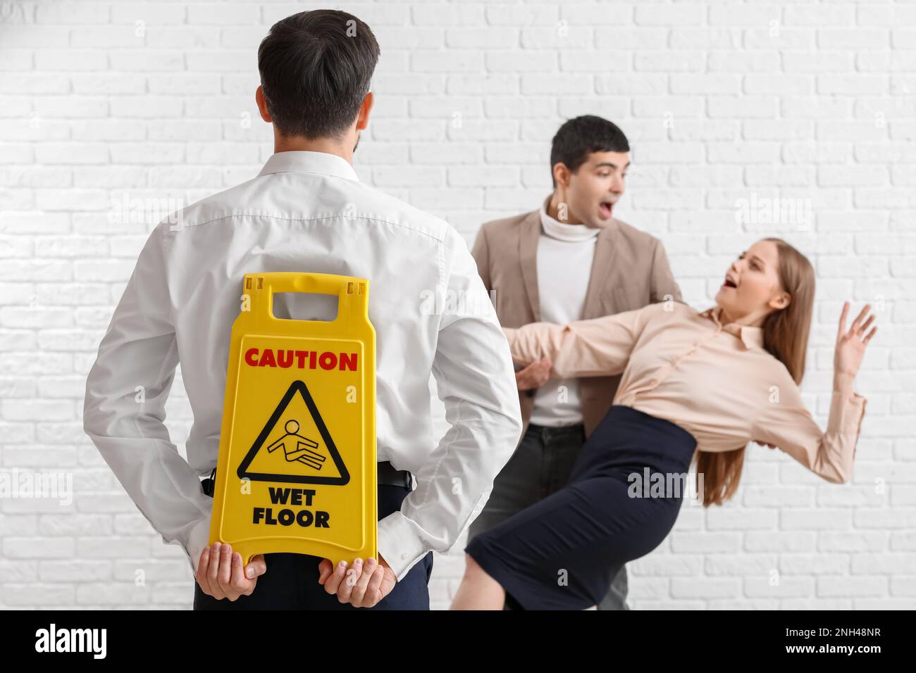 Young man with caution sign playing a prank on his colleagues against ...