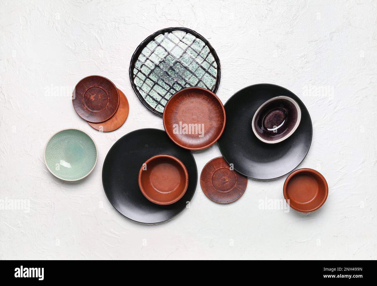 Composition with clean ceramic plates and bowls on white background ...