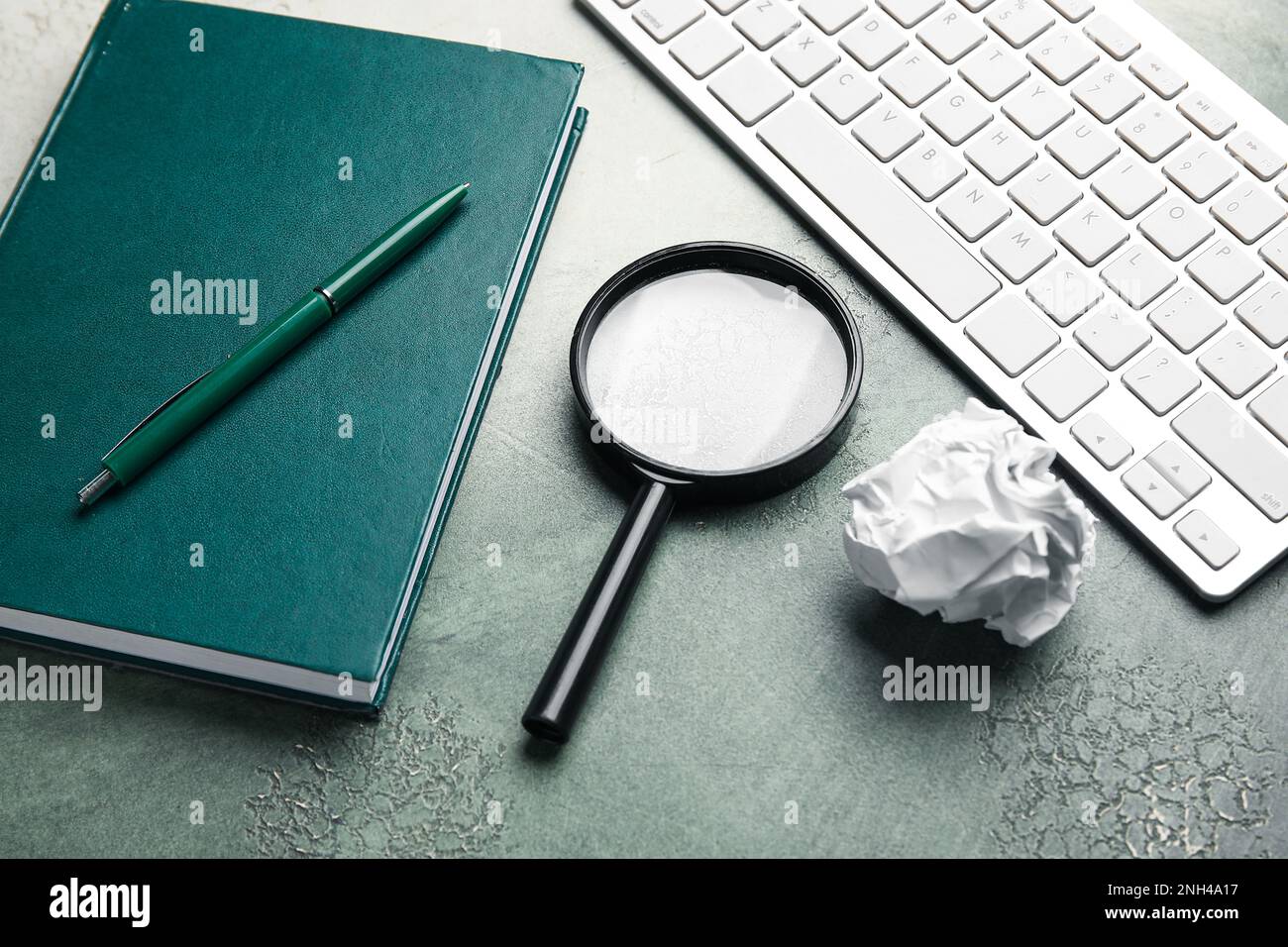 Notebook, pen, magnifier, keyboard and crumpled paper ball on grunge ...