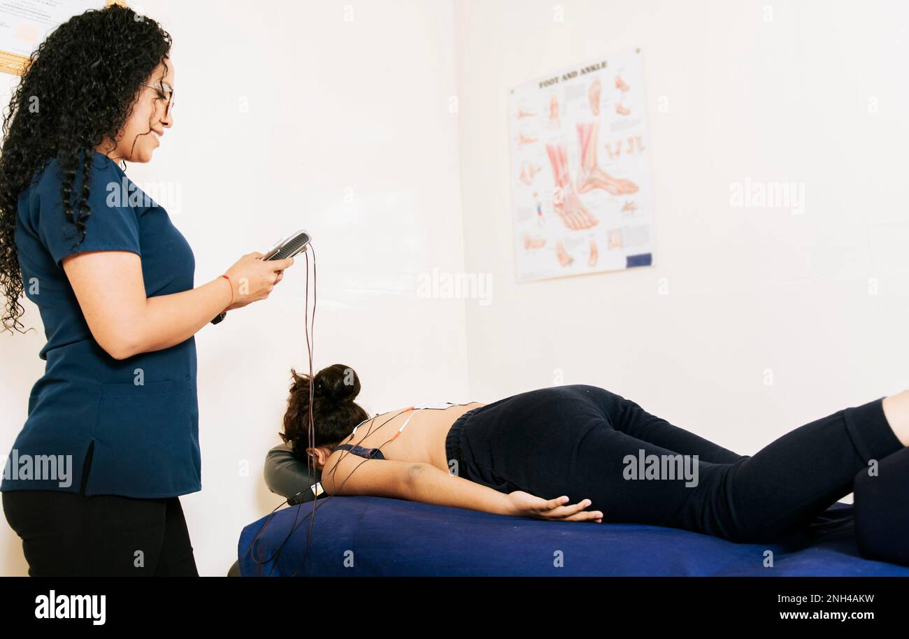 Professional physiotherapist electrostimulating a lying patient ...