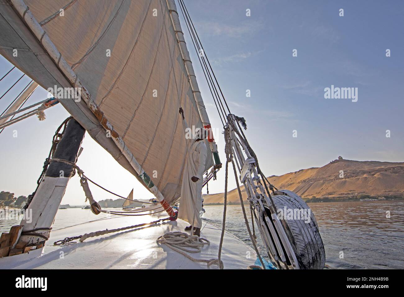 Egyptian man adjusts the sail of a felucca on the Nile, traditional ...