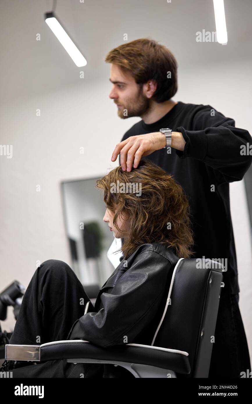 Beautiful young woman in modern hair salon. hairdresser checking ...