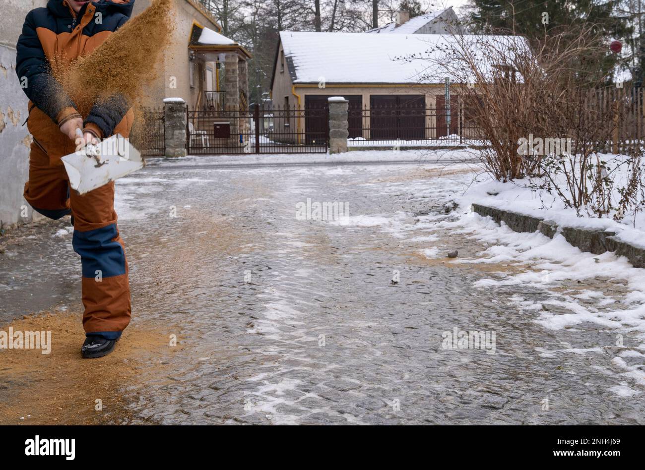Child scattering gravel sand on footpath to reduce slipperiness Stock ...