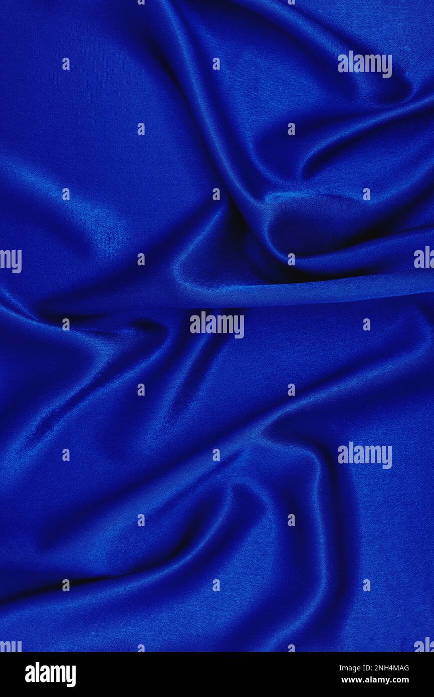 Texture of bright blue silk fabric. Smooth wavy fabric. Can be used as ...