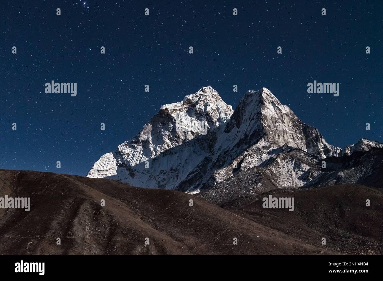 Ama Dablam mountain peak lit up by bright moonlight on a starry night ...