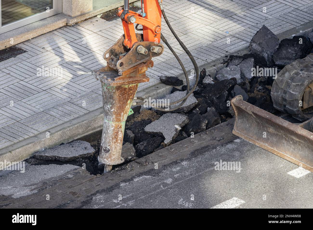 Construction machine breaking and drilling a trench in a road for ...