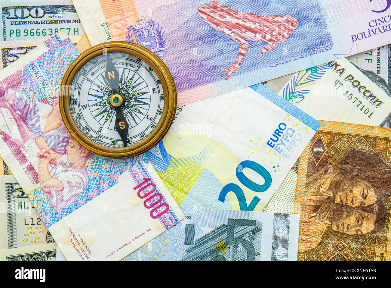 Top view of colorful world currencies with a compass laid on top ...