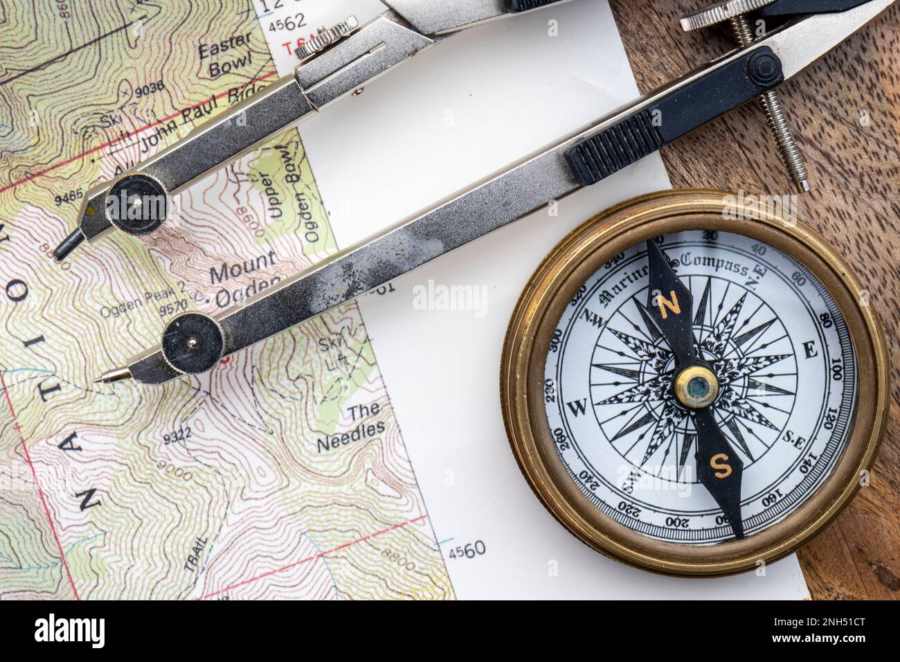 Topographical map on a wooden surface with compasses, measuring tool on ...
