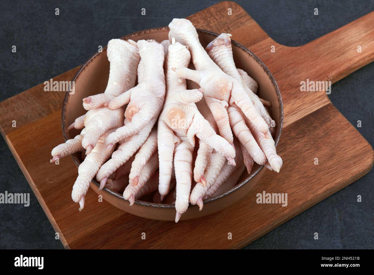 Raw chicken feet in bowl on black background Stock Photo - Alamy