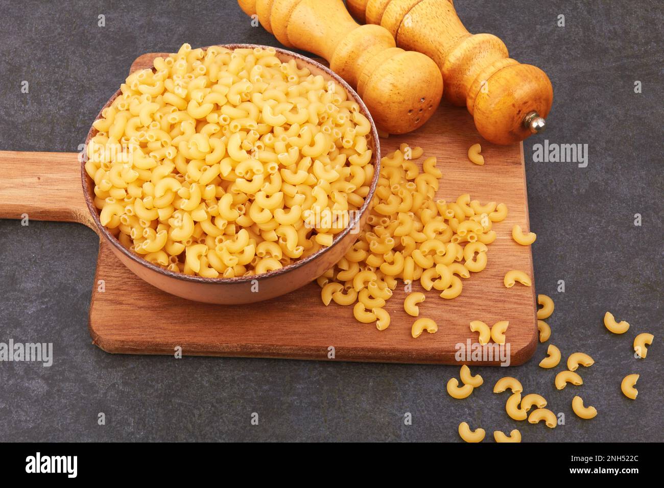 Elbow macaroni in bowl on black background Stock Photo - Alamy