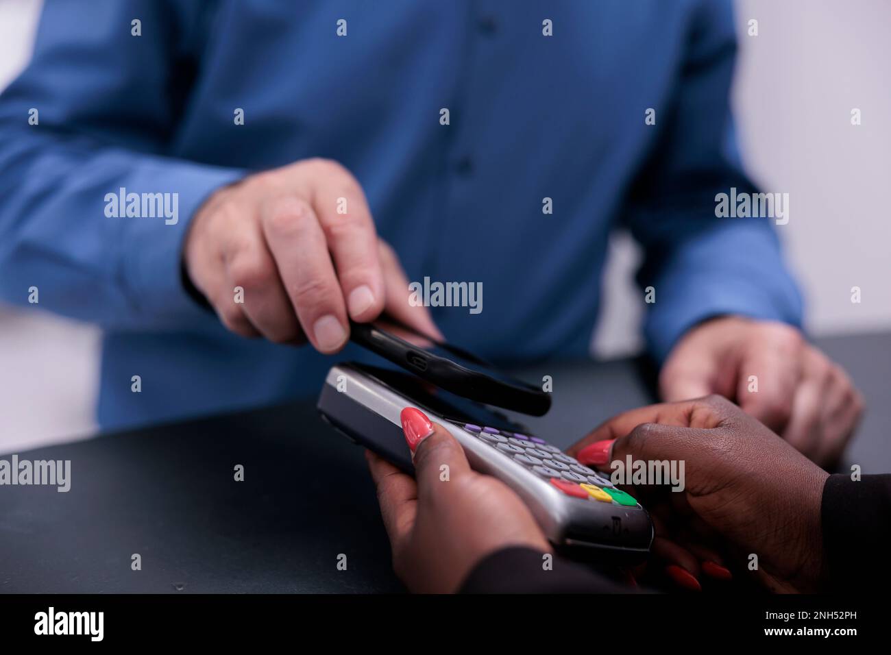 Elderly patient using phone to pay consultation at reception counter ...