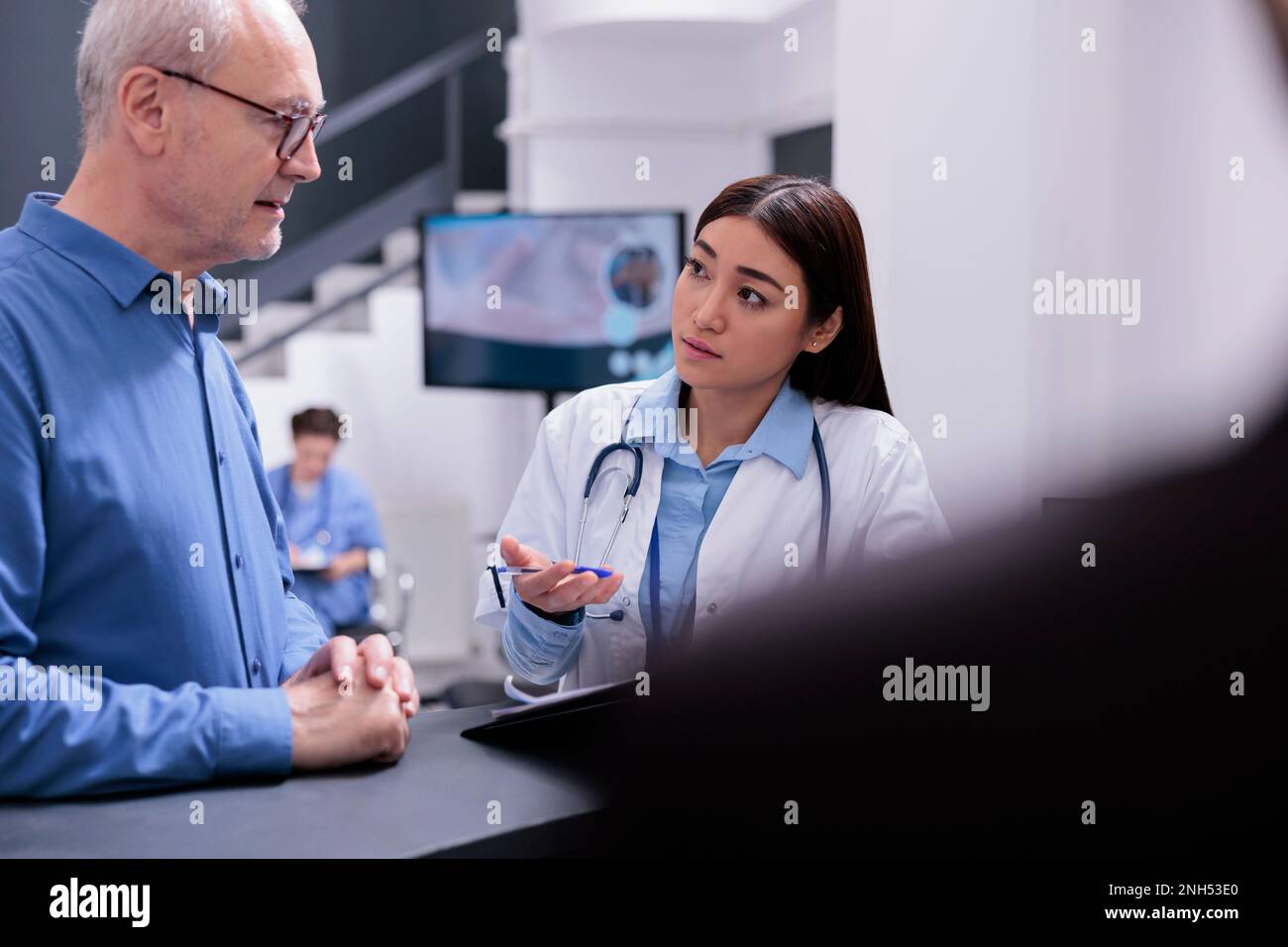Medic standing at reception desk discussing medical expertise with ...