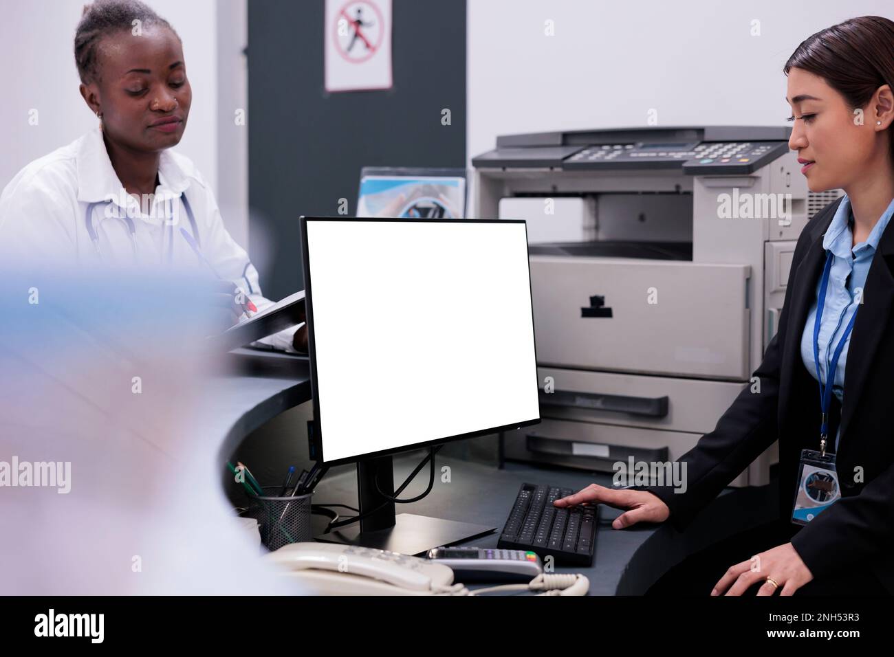 Asian reception worker using white screen on computer while working at ...
