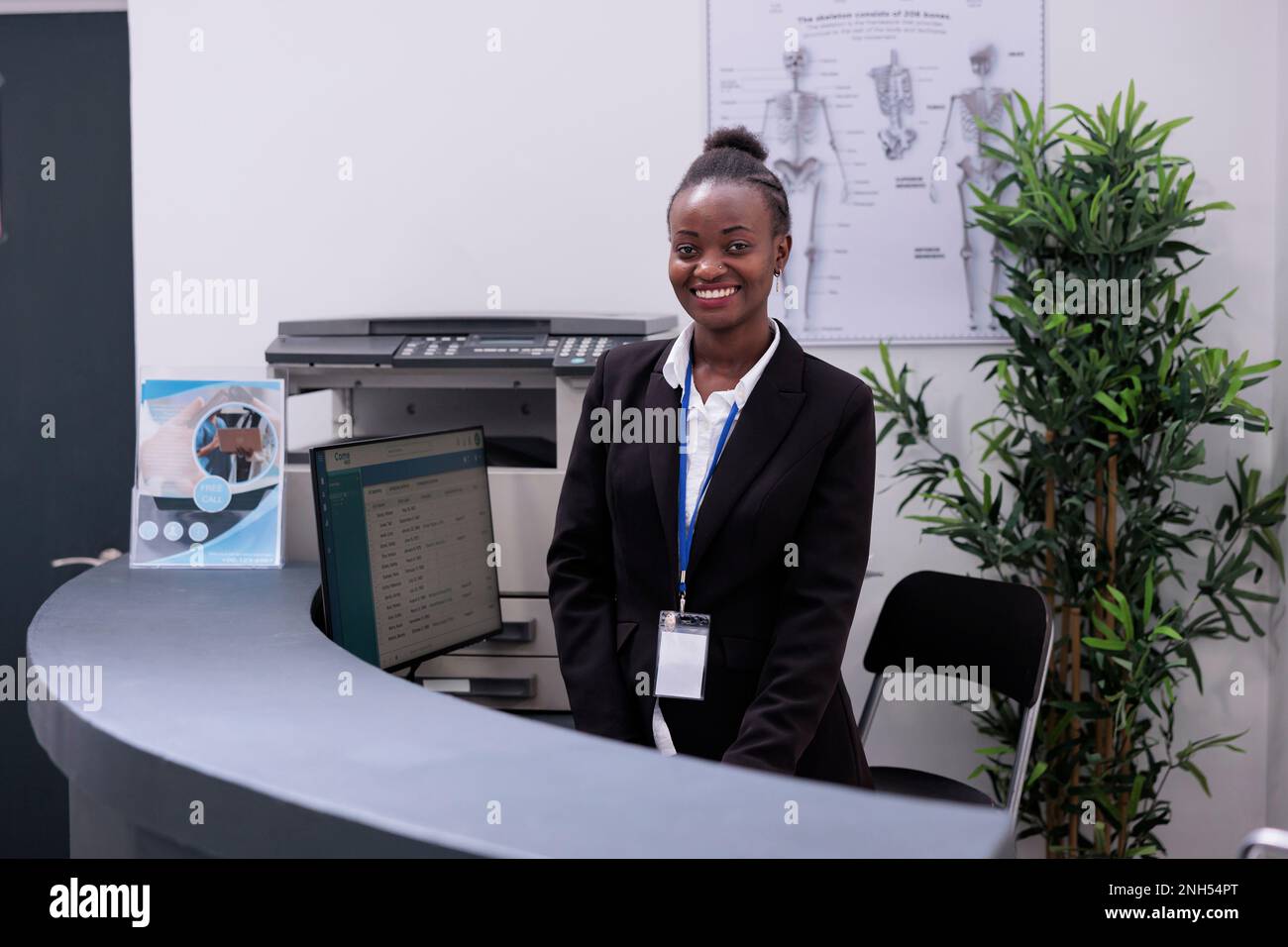 Portrait of african american receptionist standing at hospital counter ...