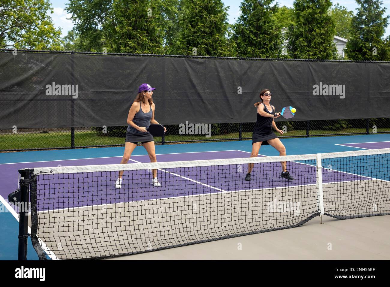 Two pickleball players in action on a suburban pickleball court during ...