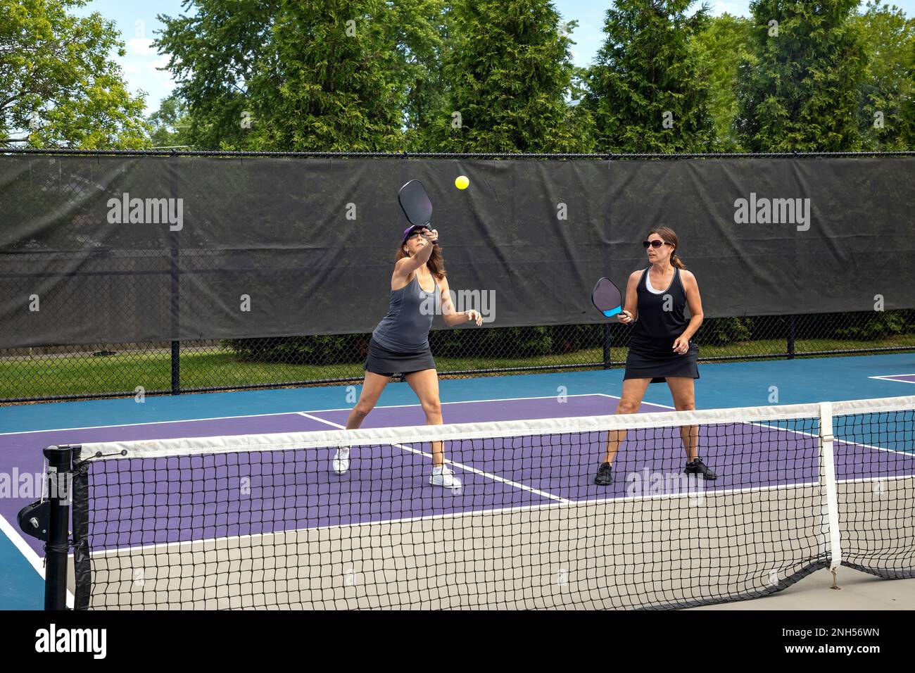 Two pickleball players prepare to return a ball on a suburban ...