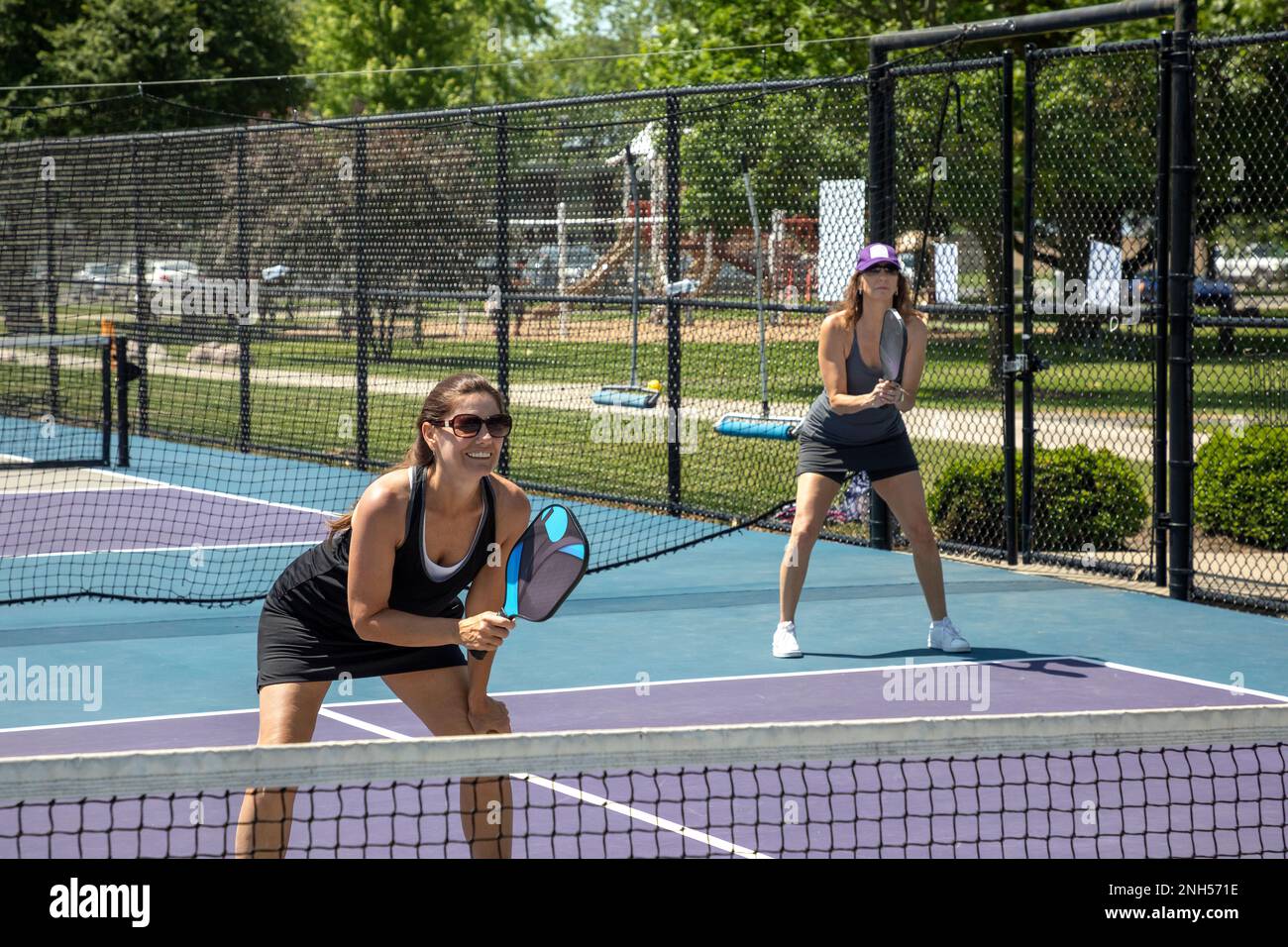 Two pickleball players prepare to return a ball on a suburban ...