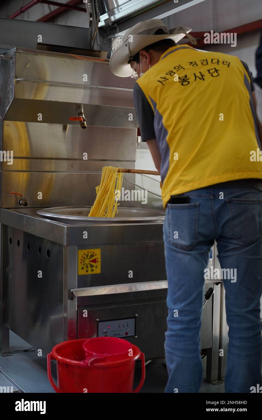 A member of the group "Stepping Stones to Love" prepares noodles to ...