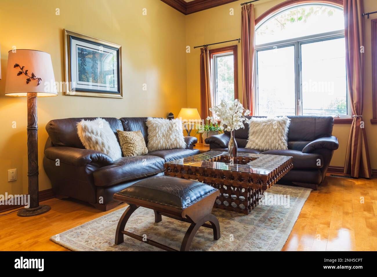 Brown leather sofas, ottoman and elaborately carved wooden glass top ...