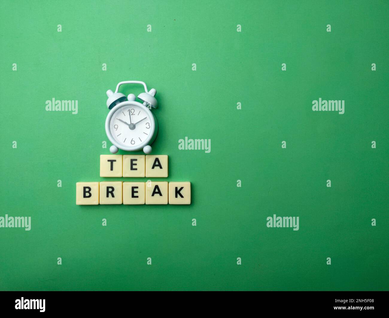 White alarm clock with the word TEA BREAK on a green background Stock ...