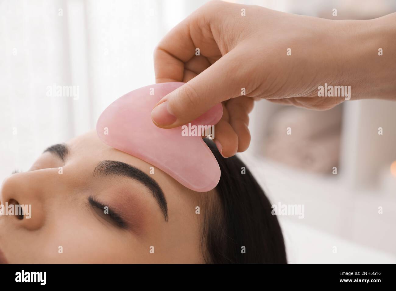 Young woman receiving facial massage with gua sha tool in beauty salon, closeup Stock Photo - Alamy