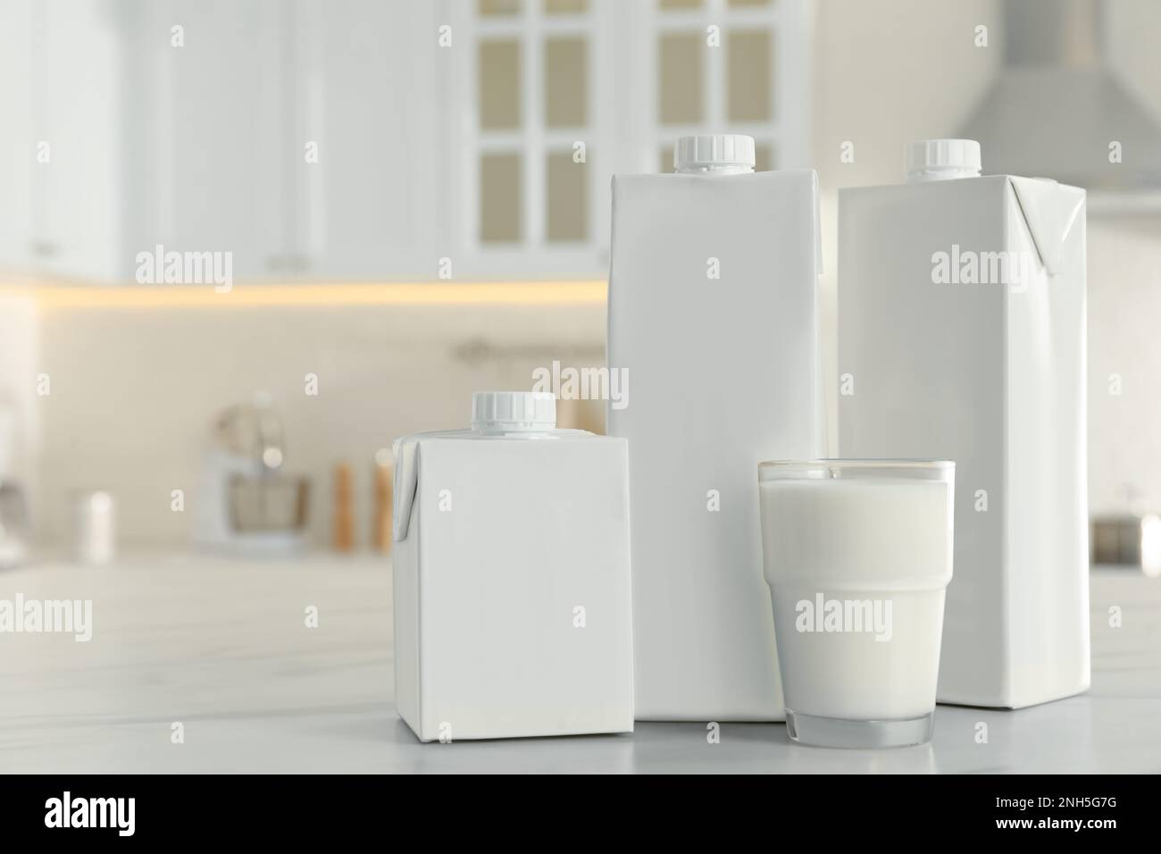 Carton boxes and glass of milk on table in kitchen, space for text ...
