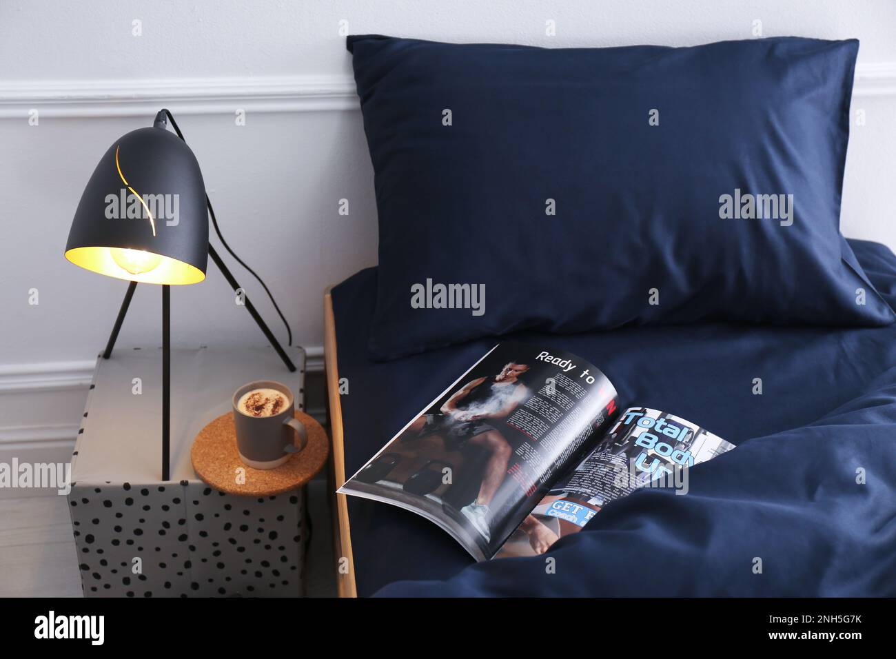 Open magazine on bed with stylish silky linens Stock Photo - Alamy