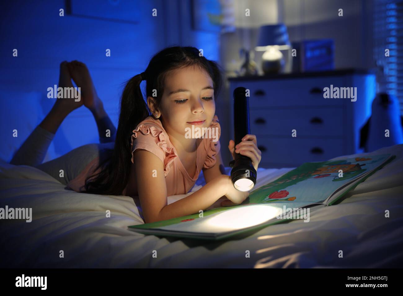 Little girl with flashlight reading fairy tale in dark bedroom Stock ...