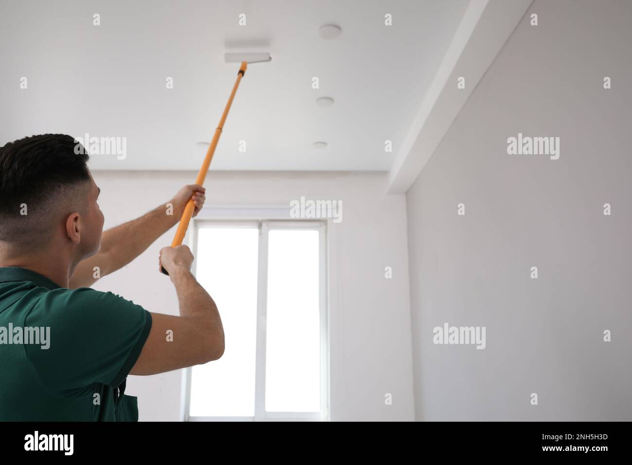 Man painting ceiling with roller in room. Space for text Stock Photo ...