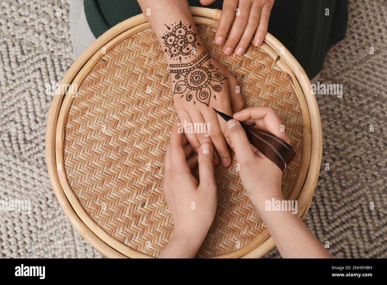 Master making henna tattoo on hand at table, top view. Traditional ...