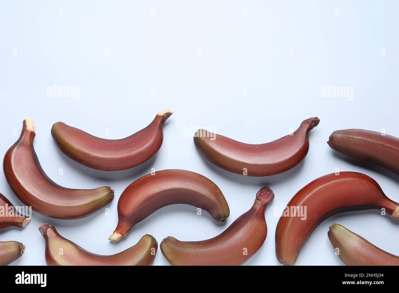 Tasty red baby bananas on light blue background, flat lay. Space for ...