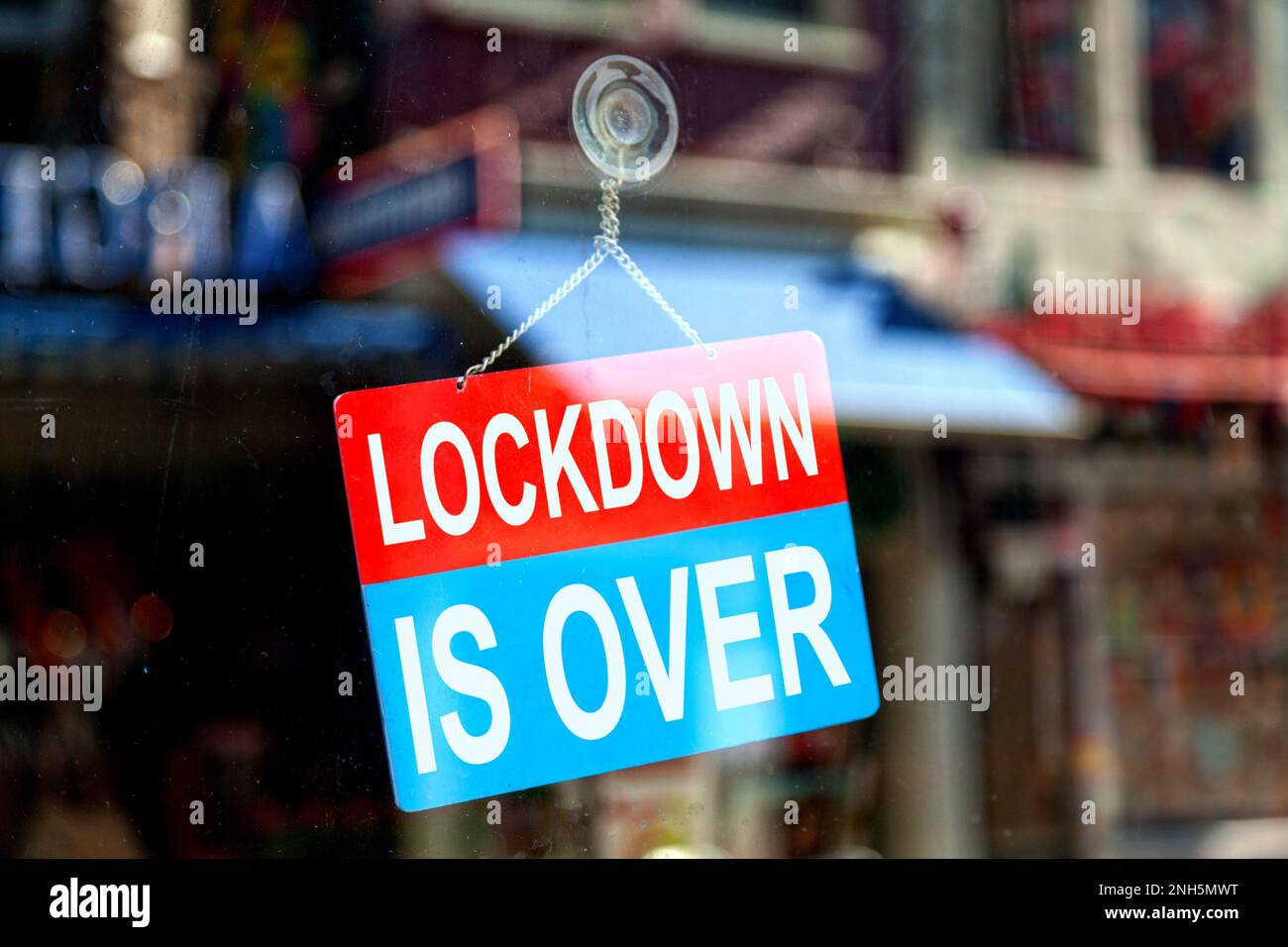 Red and blue sign in the window of a shop saying "Lockdown is over ...