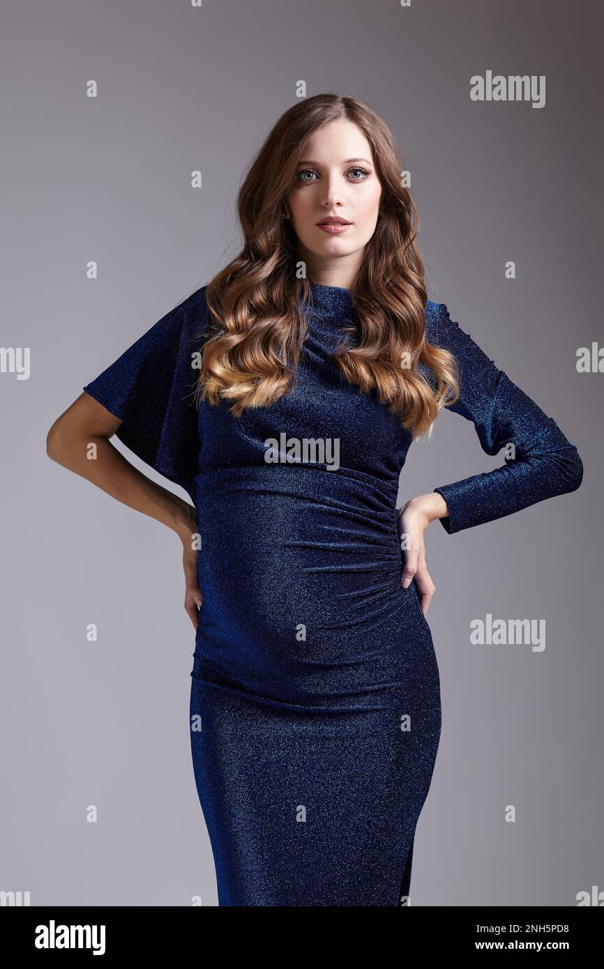 Portrait of young pretty pregnant woman on gray studio background ...