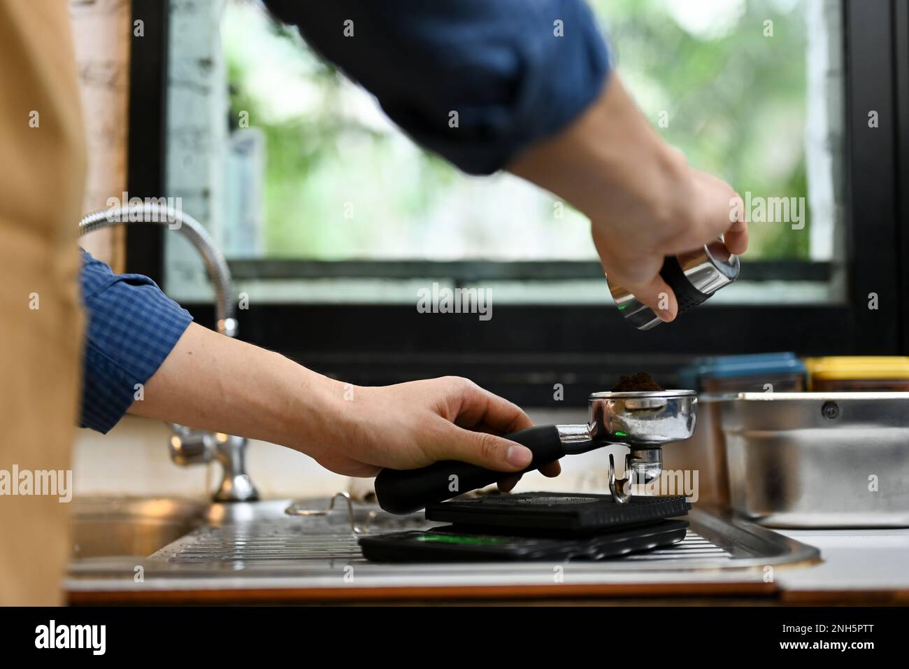 Close-up image of a professional male barista adding coffee powder into ...