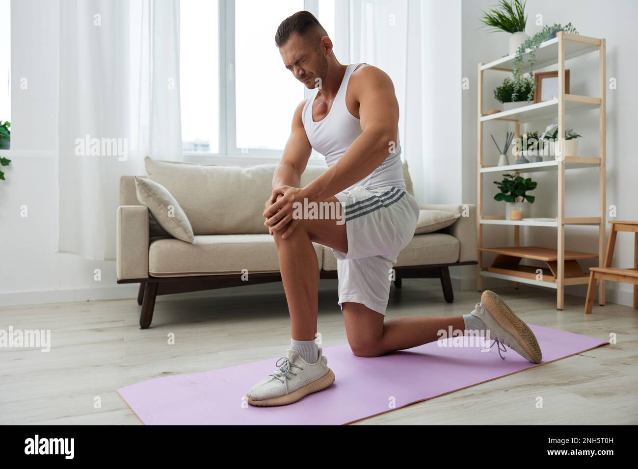 Man sports pain in the side and leg during a workout at home, pumped up ...