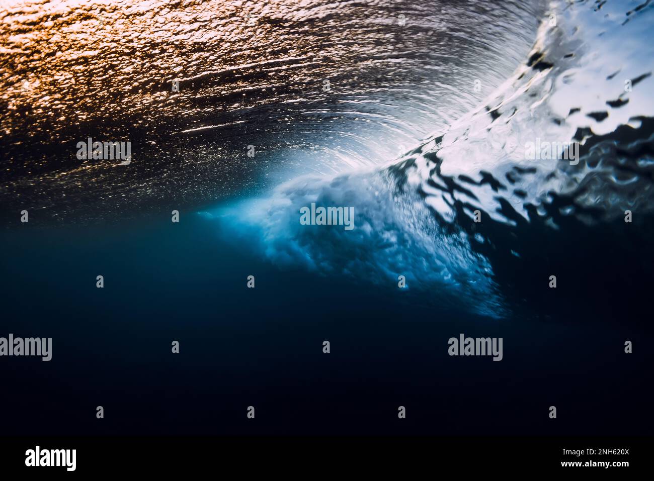 Barrel wave breaking in ocean with sunset or sunrise light. Underwater ...