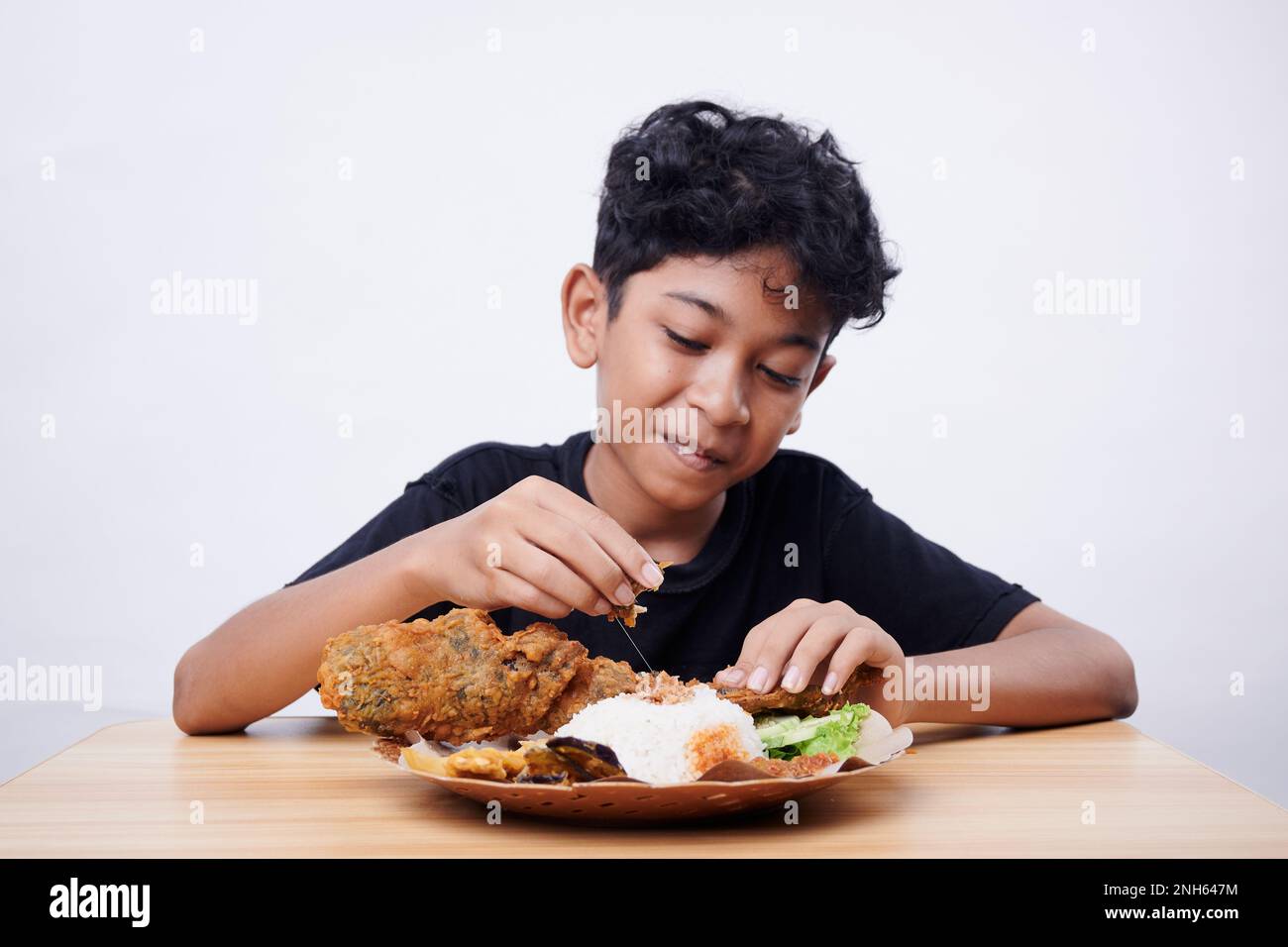 Little Boy eating Fried Fish and rice at home Stock Photo - Alamy