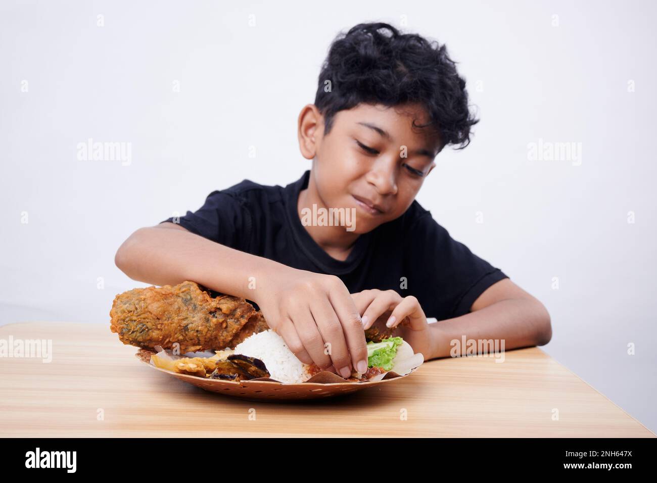 Little Boy eating Fried Fish and rice at home Stock Photo - Alamy