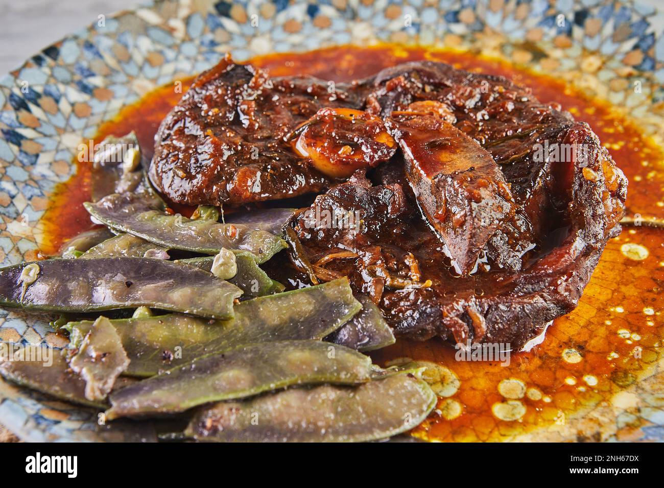 Lamb confit with snow peas in sauce on plate Stock Photo - Alamy