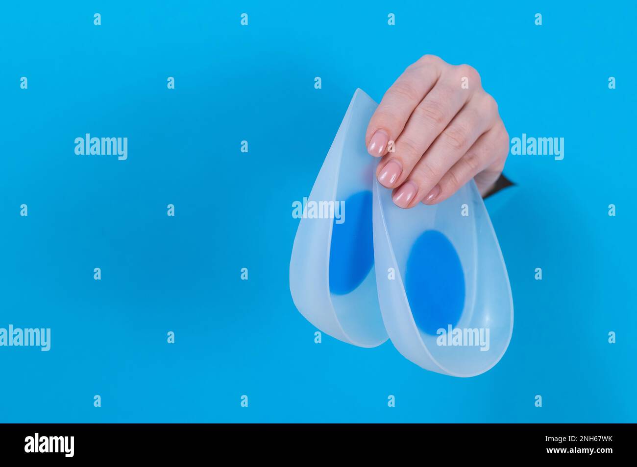 Woman holding orthopedic silicone heel pads. A woman's hand sticks out ...