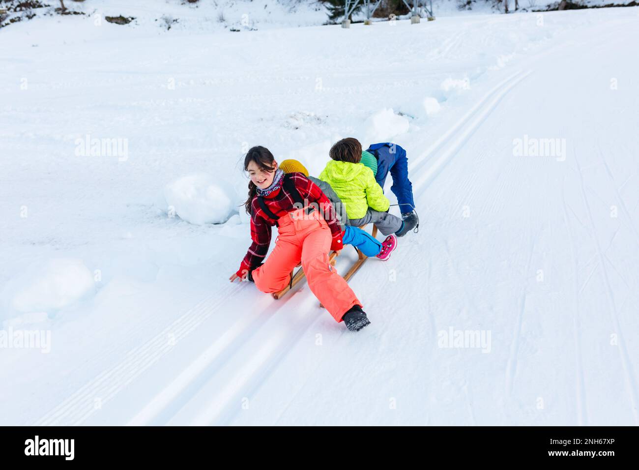 group of children in bright winter clothes riding one wooden sled going ...