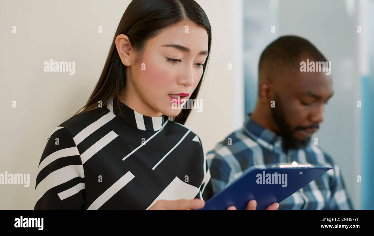 Female candidate looking at recruitment files in queue at job interview ...