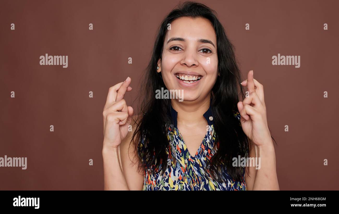 Young adult feeling hopeful about wish praying for good luck, posing ...
