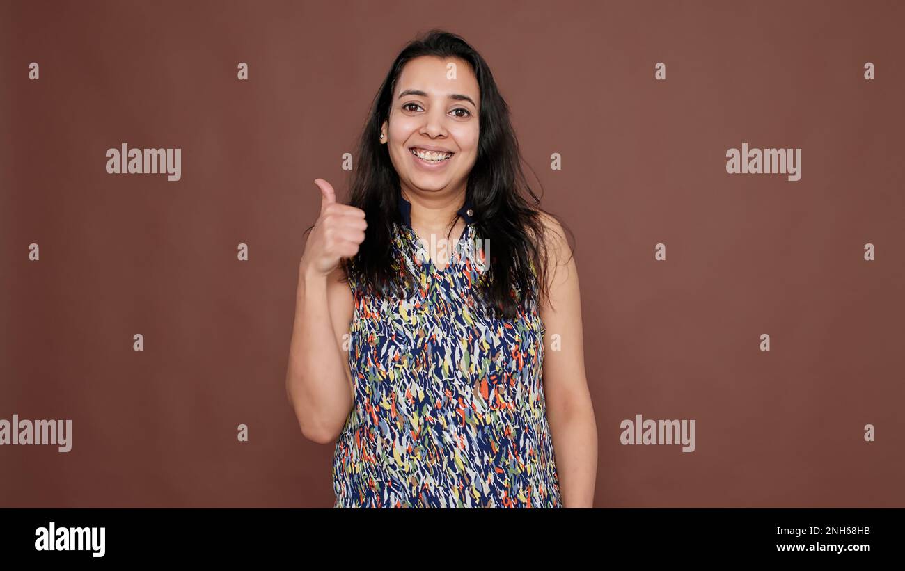 Portrait of indian woman doing thumbs up gesture on camera, giving like ...