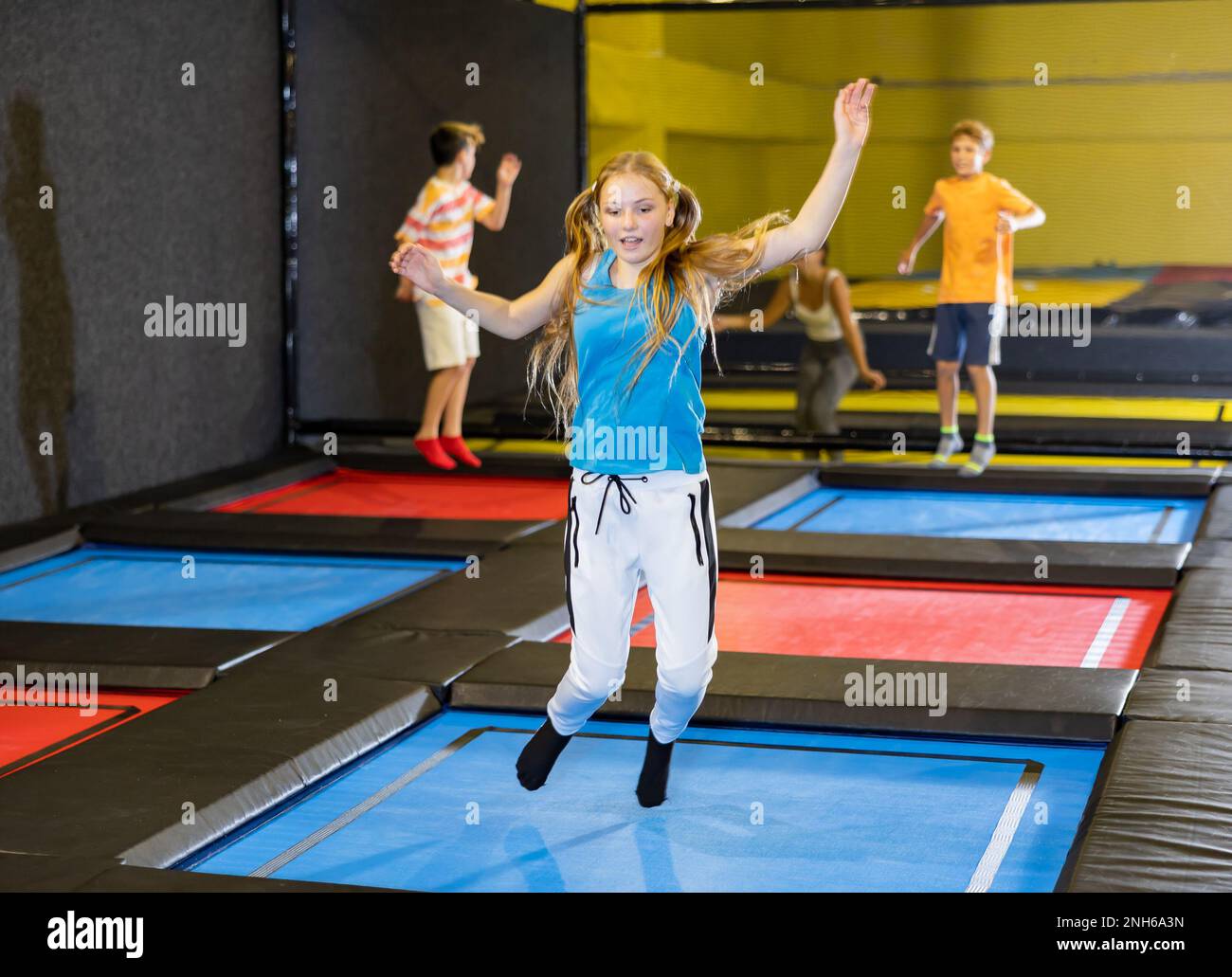 Happy cute little girl jumping on trampoline indoors Stock Photo - Alamy