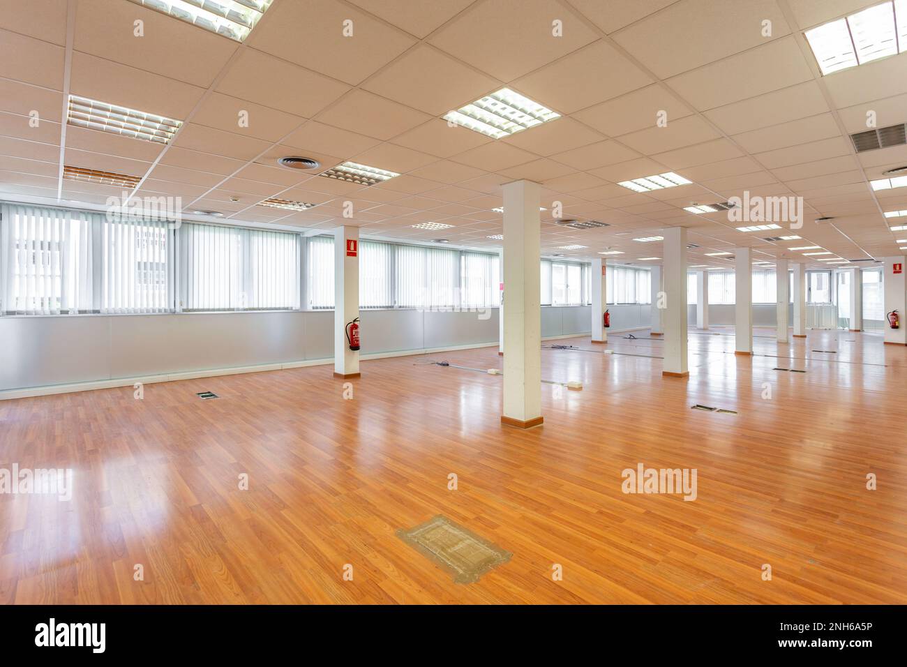Large empty space with ceiling tiles, fluorescent lights, light brown ...